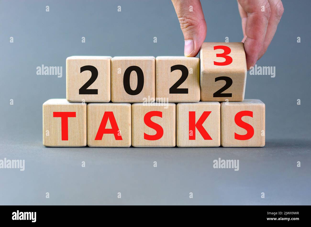 2023 tasks new year symbol. Businessman turns a wooden cube and changes words Tasks 2022 to ...