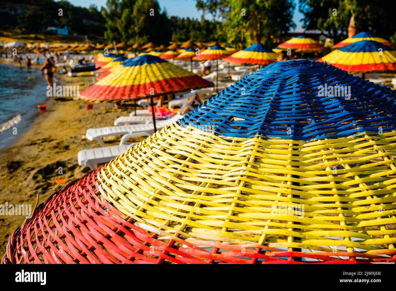 Colorful straw beach umbrellas at the seaside Stock Photo - Alamy
