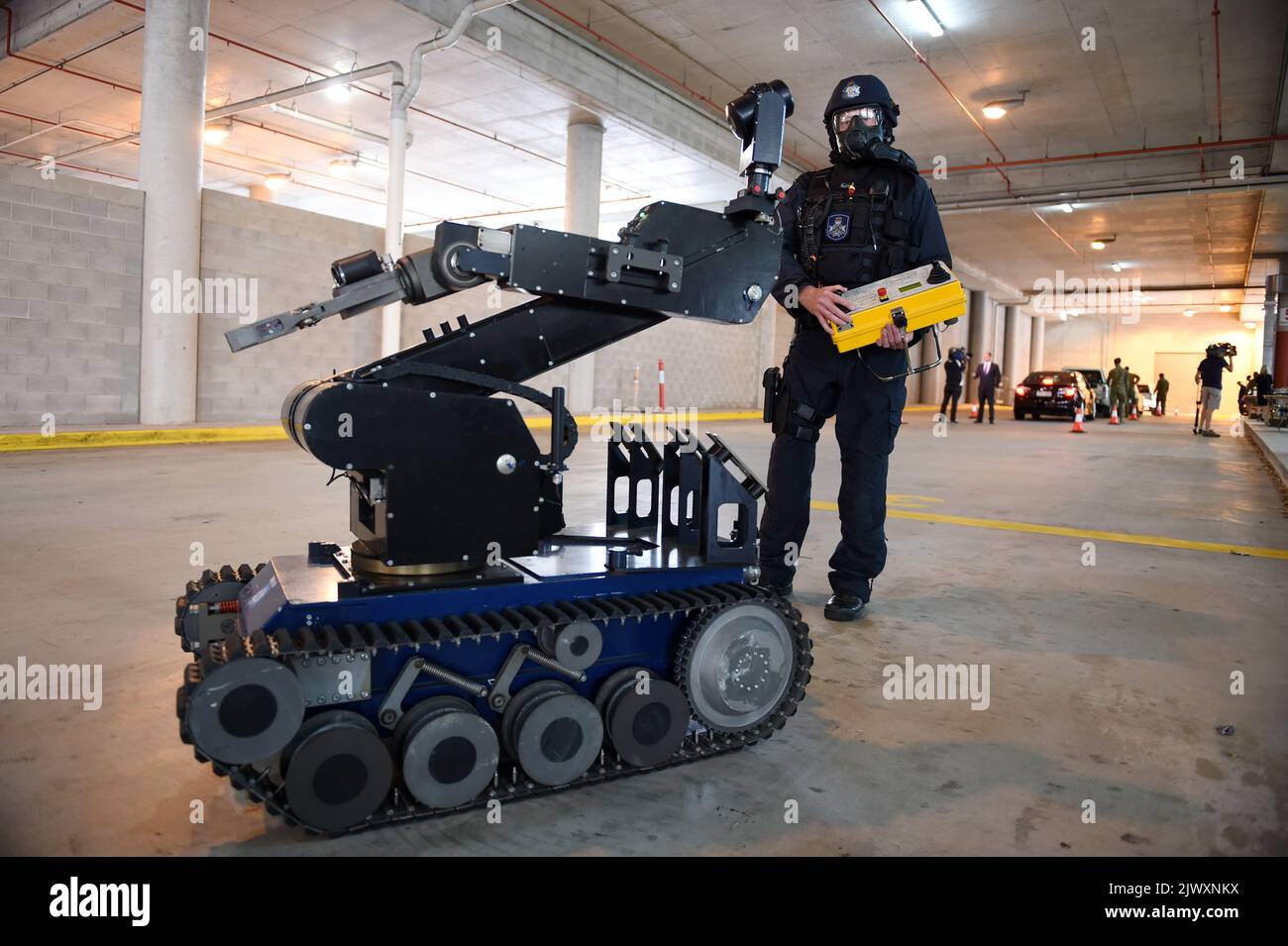 A police officer in tactical gear operates a bomb disposal robot during ...