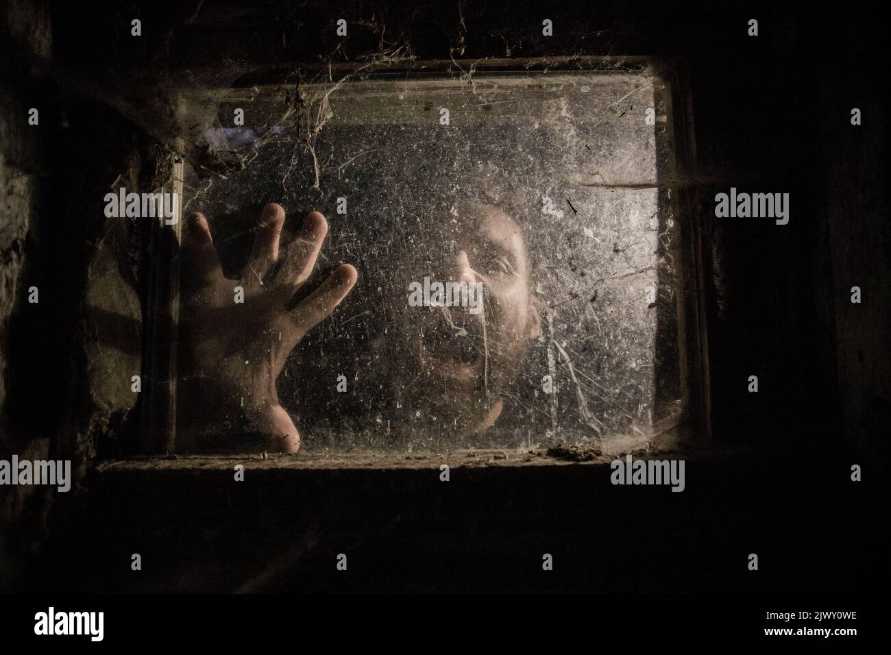 scary man behind window with spider nets at night Halloween horror ...