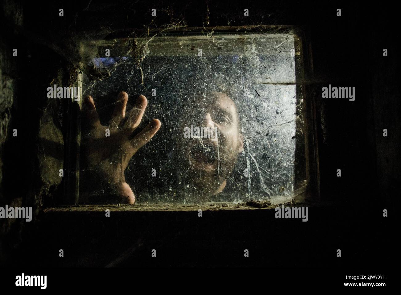 scary man behind window with spider nets at night Halloween horror ...