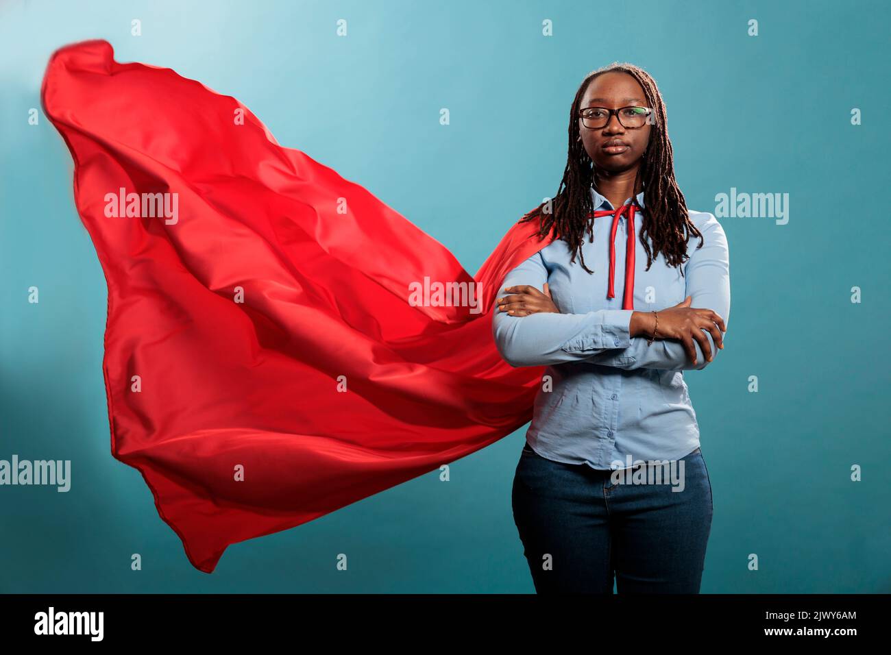 Confident and brave young superhero woman standing with arms crossed ...
