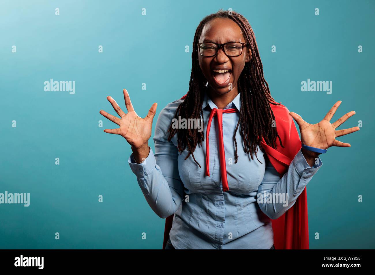 Young adult justice defender wearing red cape yelling in fear at camera ...