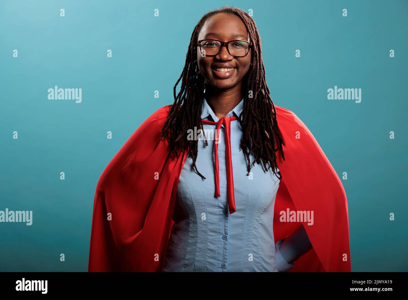 Smiling heartily young adult superhero woman wearing red hero cape ...