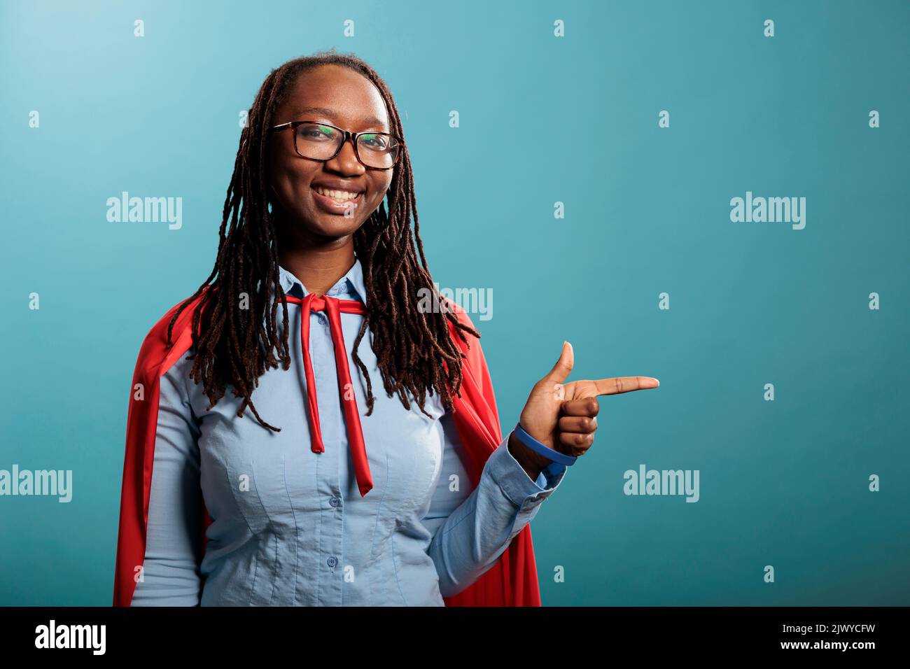 Confident and cheerful smiling superhero woman wearing mighty hero cape ...