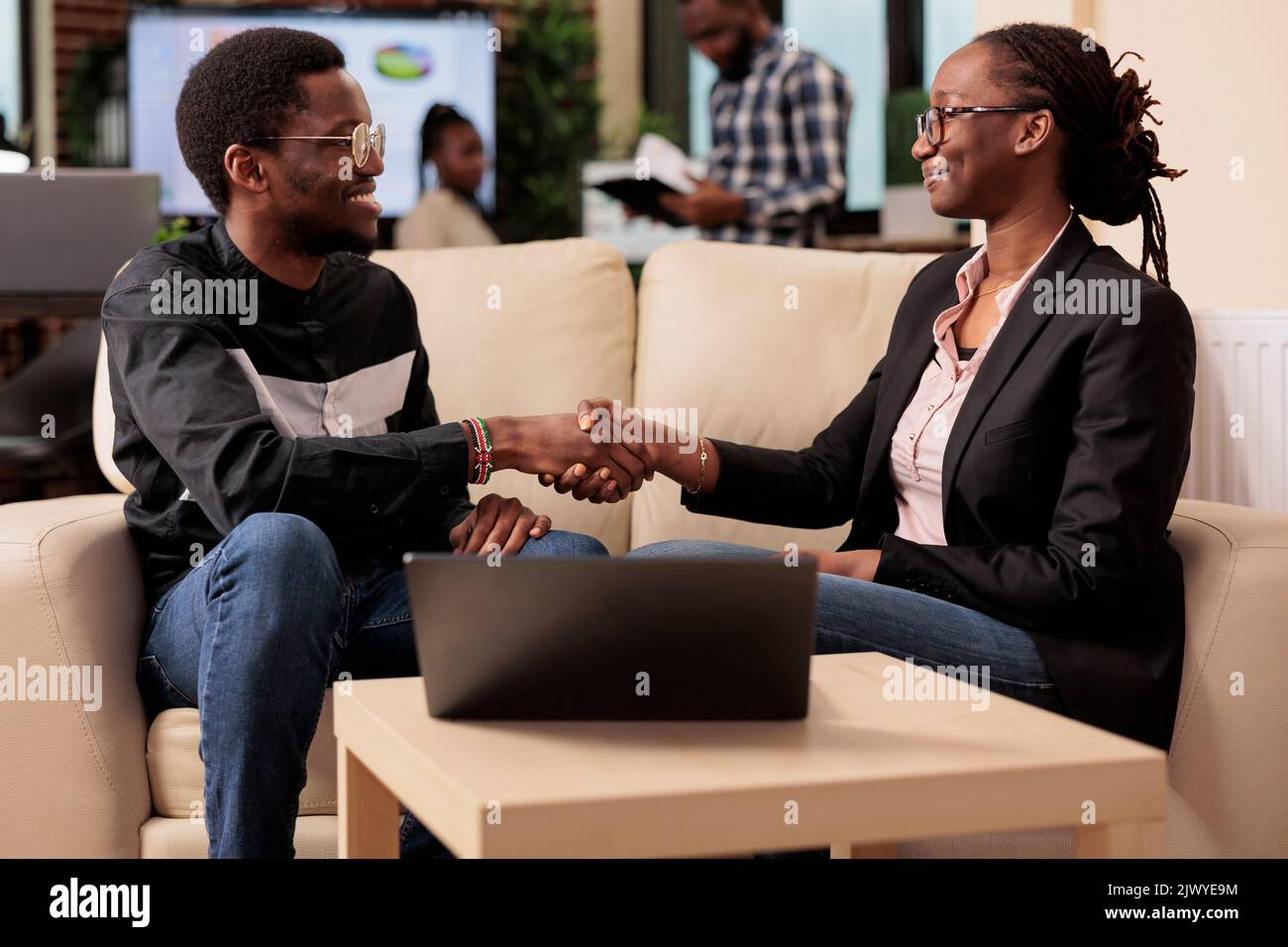 Work colleagues doing handshake on partnership, agreeing on startup ...