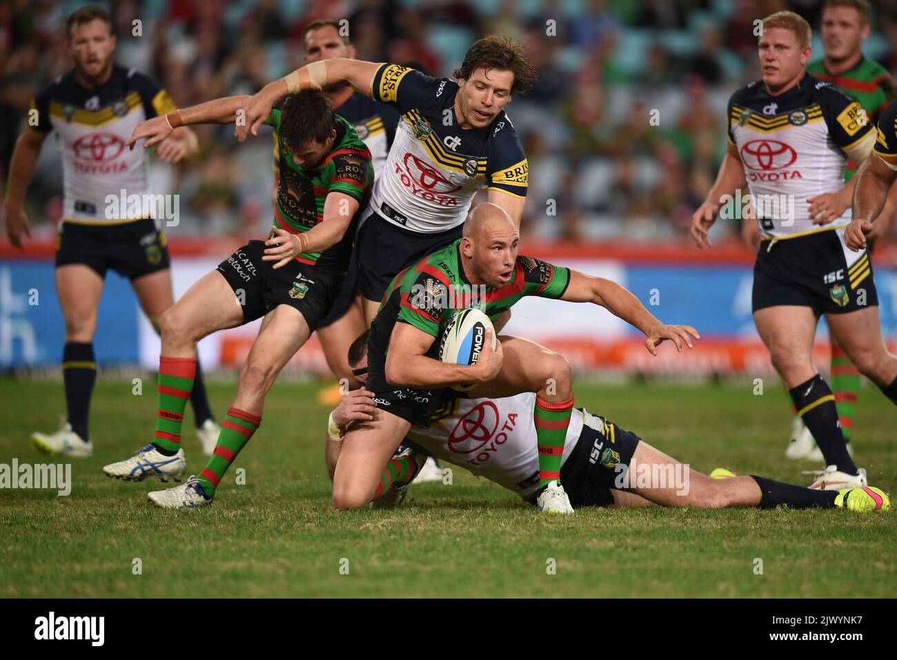 Ben Lowe of the Rabbitohs is tackled by Rory Kostjasyn and Ethan Lowe of the Cowboys during the ...