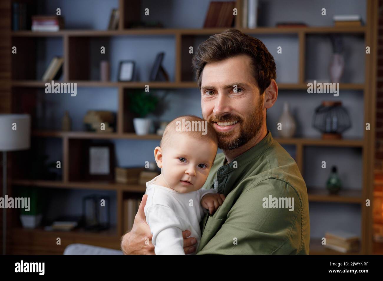 Close-up portrait of a father with a baby in his arms. Dad loves his ...