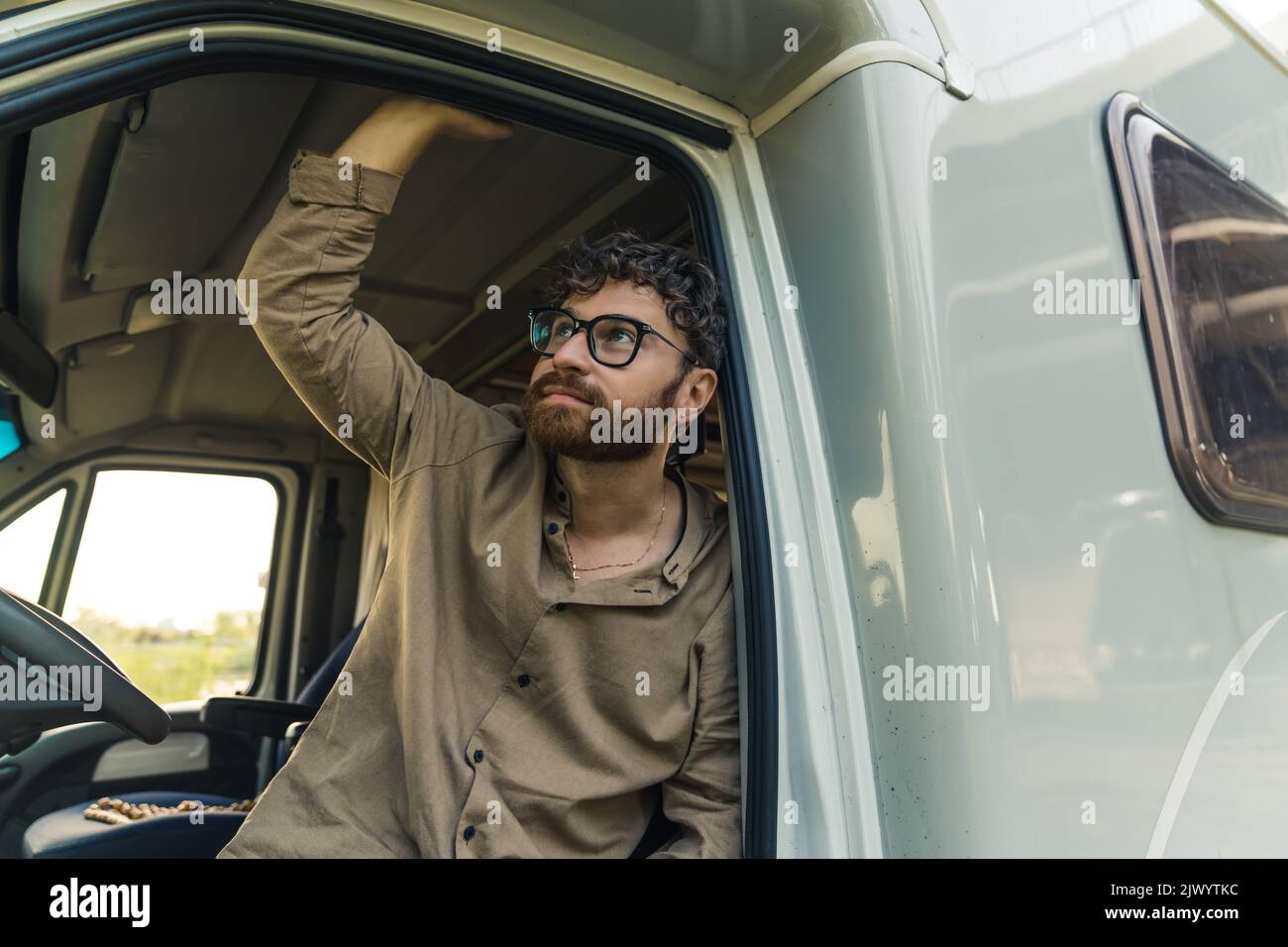 Thoughtful stylish young bearded man sitting on the driver seat of a ...
