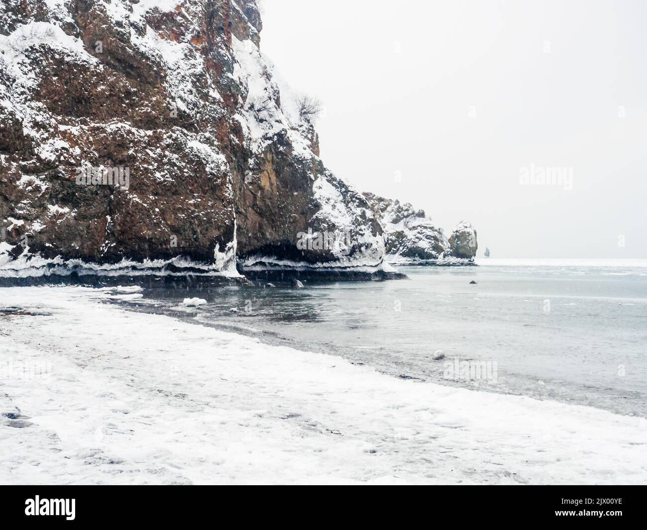 Sea beach with cliff covered with snow Stock Photo - Alamy