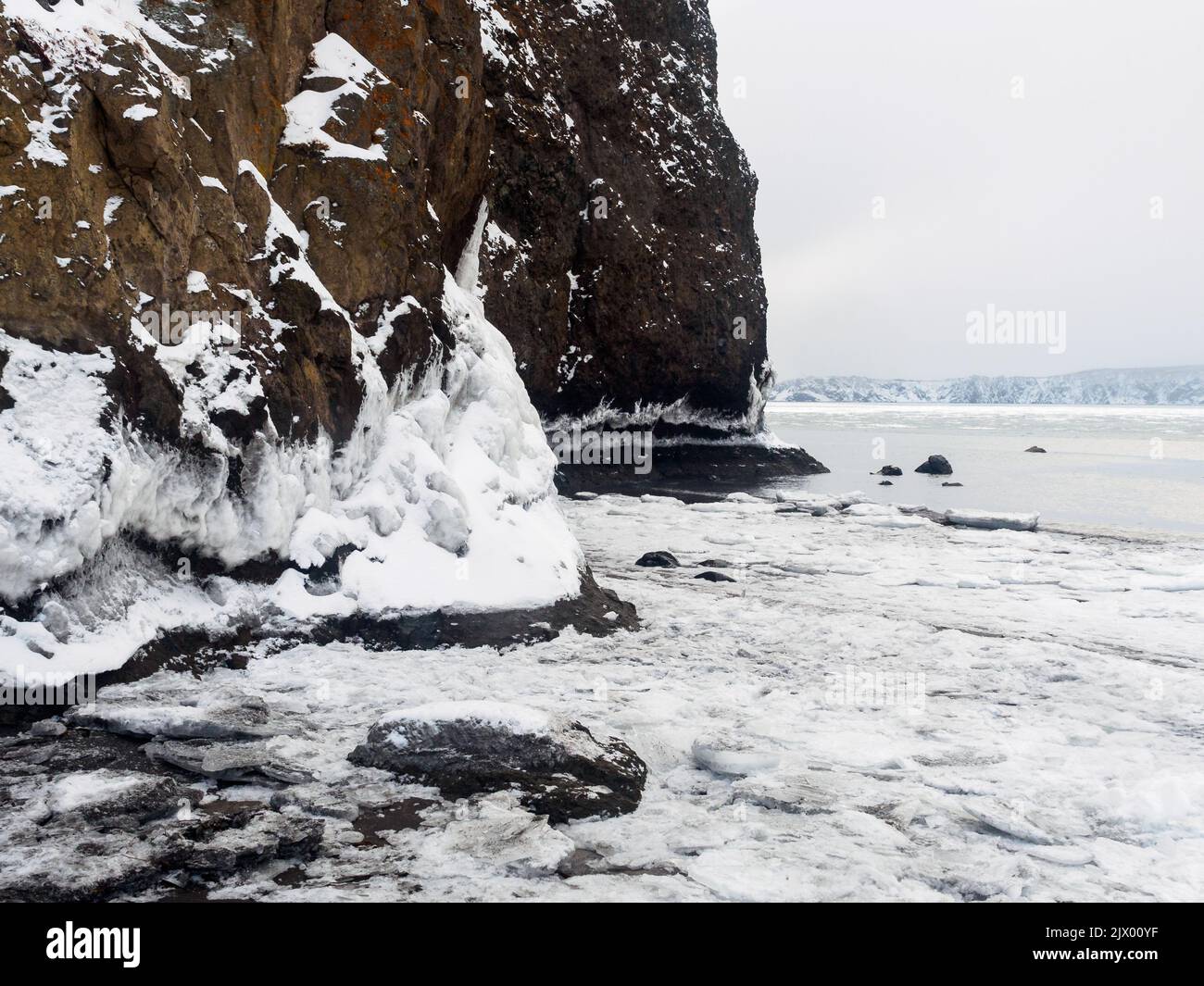 Cliff rising from iced and snowed sea Stock Photo - Alamy