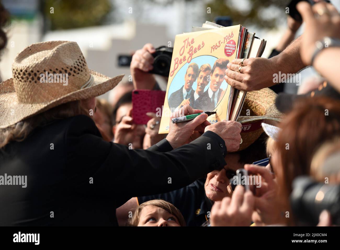 Barry Gibb of the Bee Gees (left) signs autographs as he attends the ...