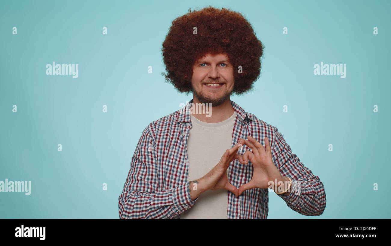 Man in love. Smiling man 30s with lush hairstyle makes heart gesture ...