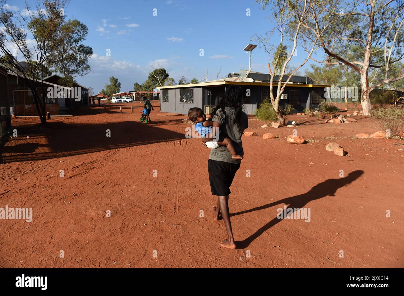 Young mothers walk with their children at the Mutitjulu aboriginal ...