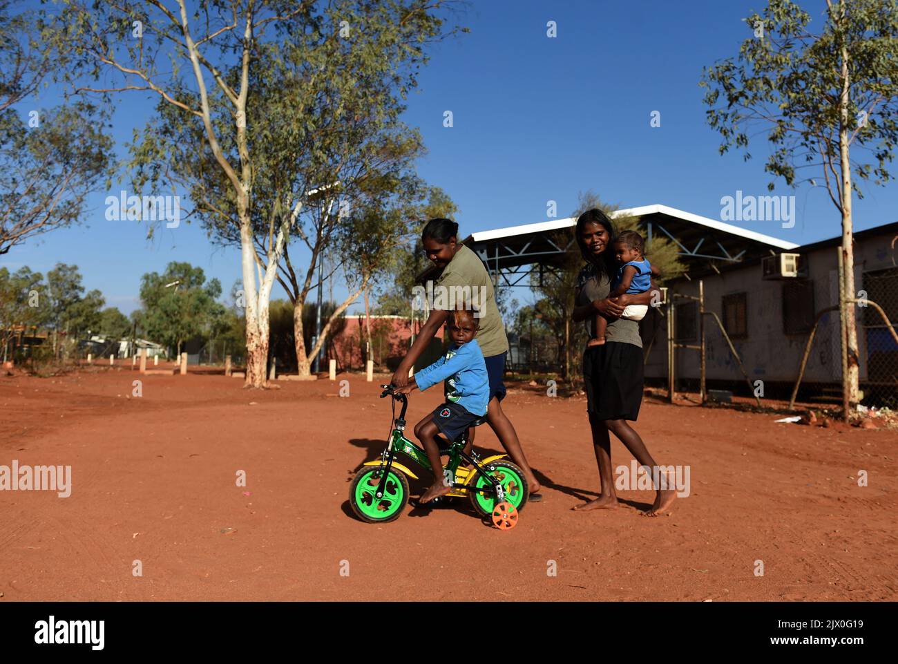 Young mothers walk with their children at the Mutitjulu aboriginal ...