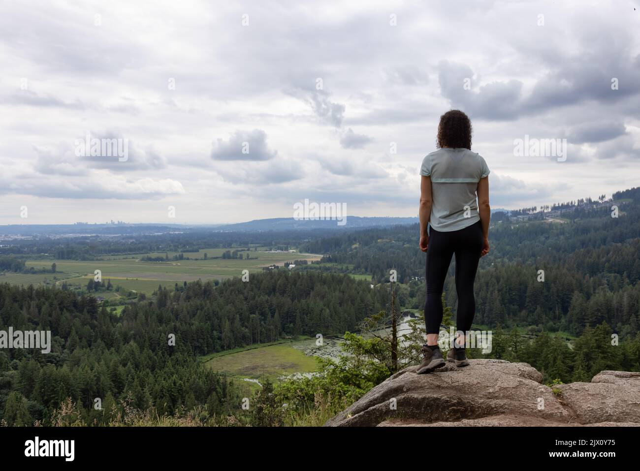 Adventurous Woman Standing on top of a rock overlooking the Canadian ...