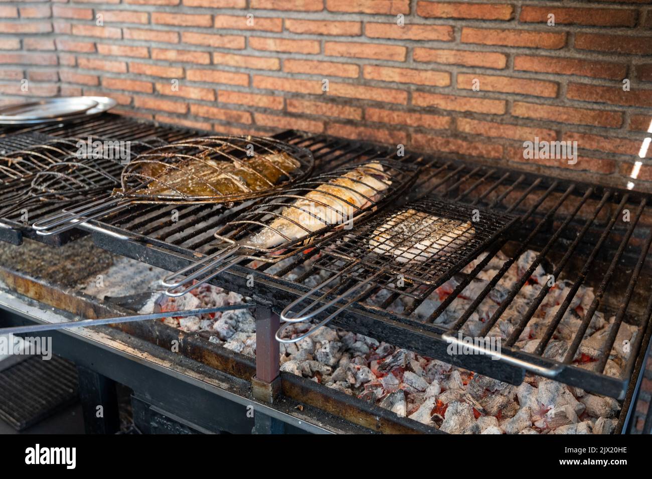 Fresh fish grilling on old charcoal parrillas white fish sea bass and ...
