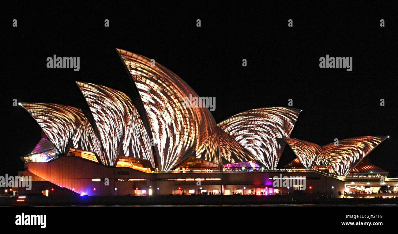 The sails on the Sydney Opera House are seen lit with an art ...