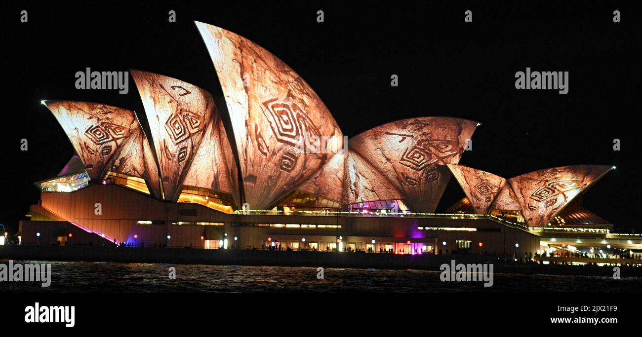 The sails on the Sydney Opera House are seen lit with an art ...
