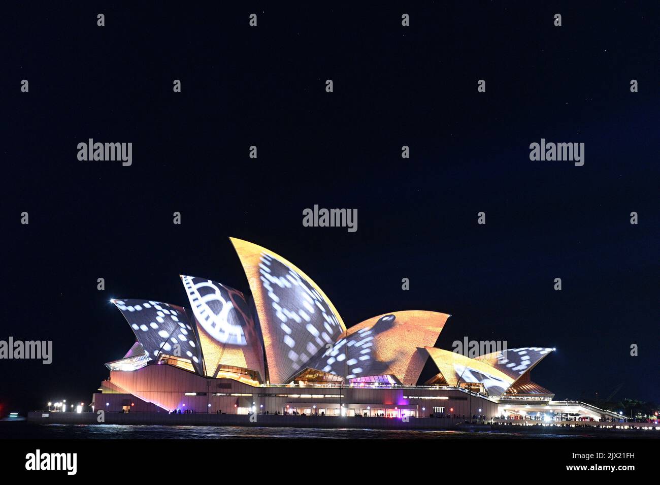 The sails on the Sydney Opera House are seen lit with an art ...