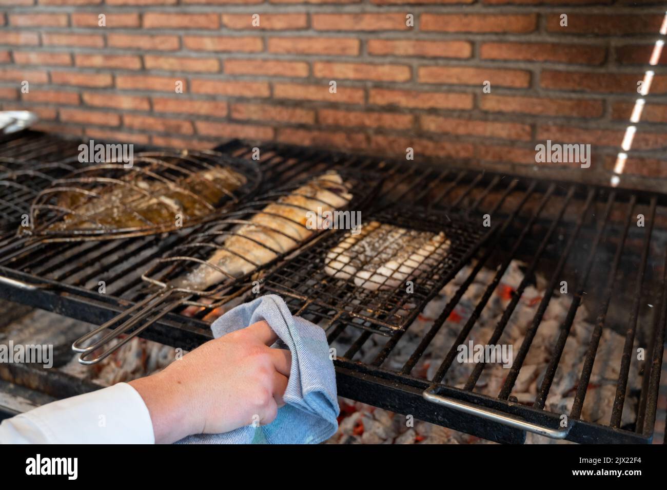 Fresh fish grilling on old charcoal parrillas white fish sea bass and ...
