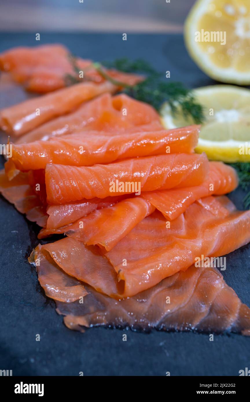 Slices of tasty smoked Scottish salmon fish served on black plate with ...
