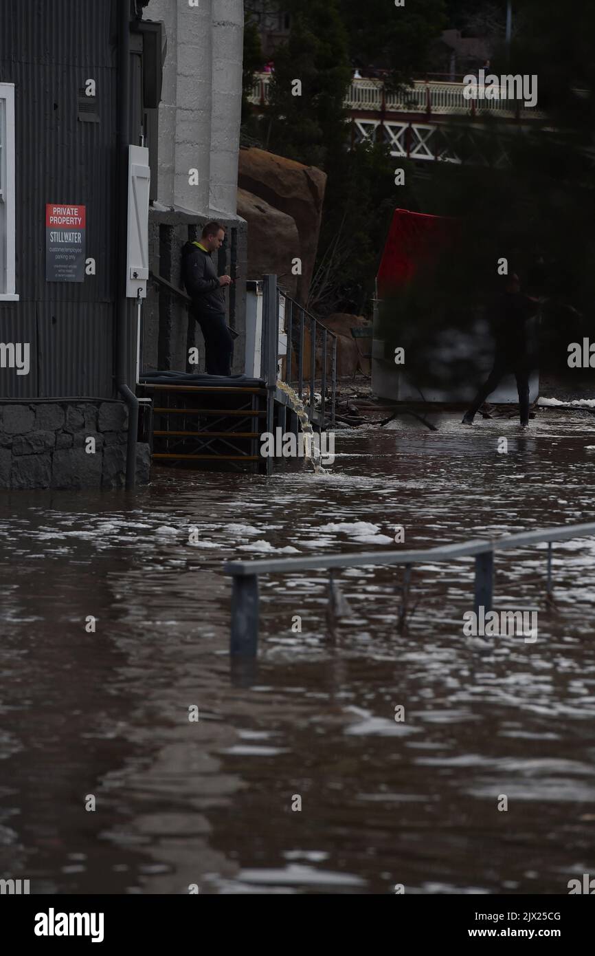 Local residents and tourists watch as flood waters rise as high tide ...