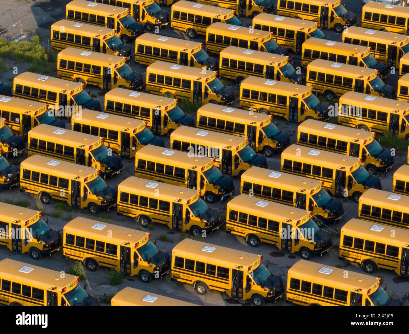 A high aerial photo above a parking lot with rows of yellow school ...