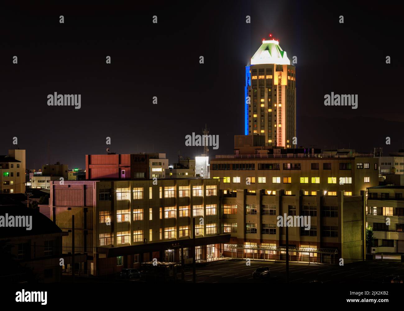 High rise building towers over lit multi-story school at night Stock ...