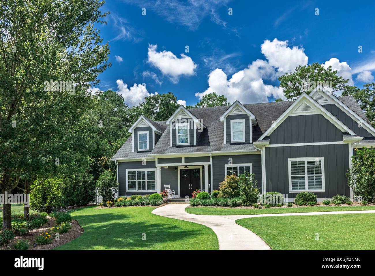 A large gray craftsman new construction house with a landscaped yard ...