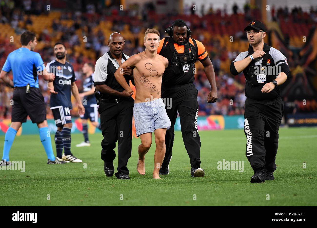 Security guards remove a streaker who ran onto the field during the ...