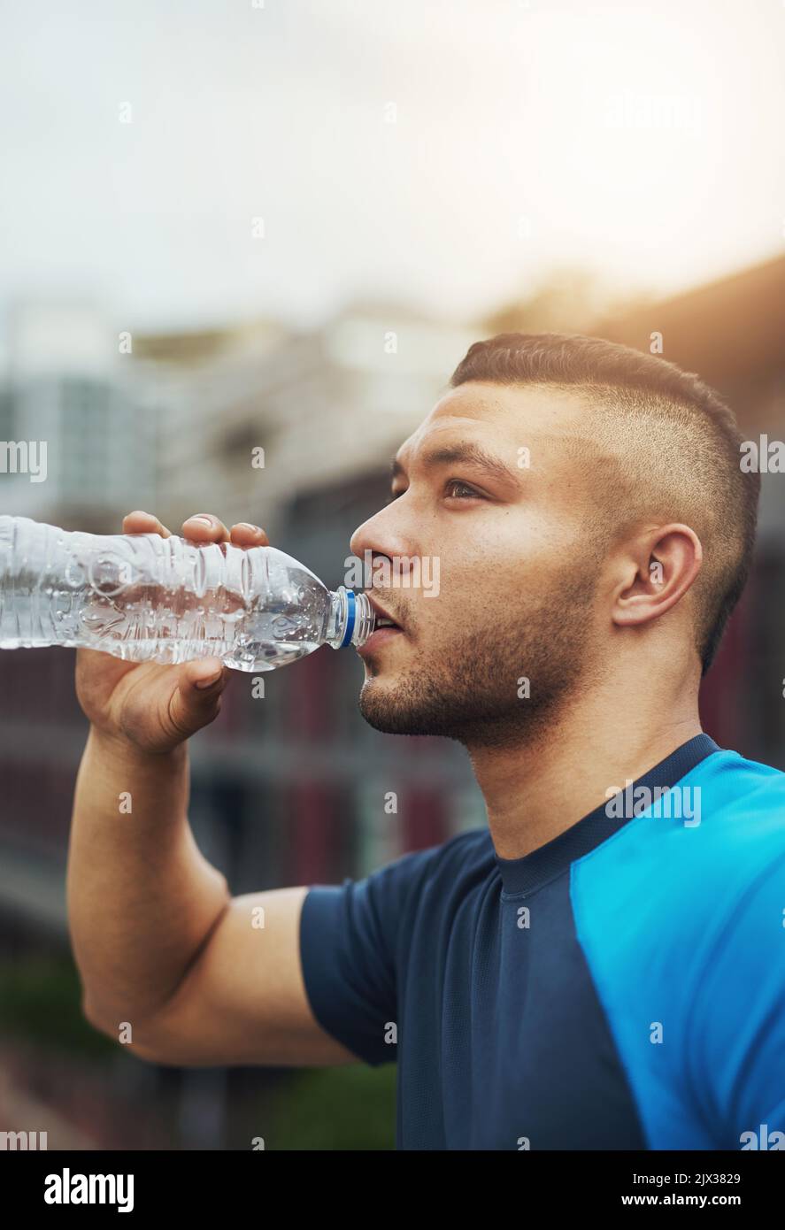 Staying hydrated. a young man drinking from his water bottle while out ...