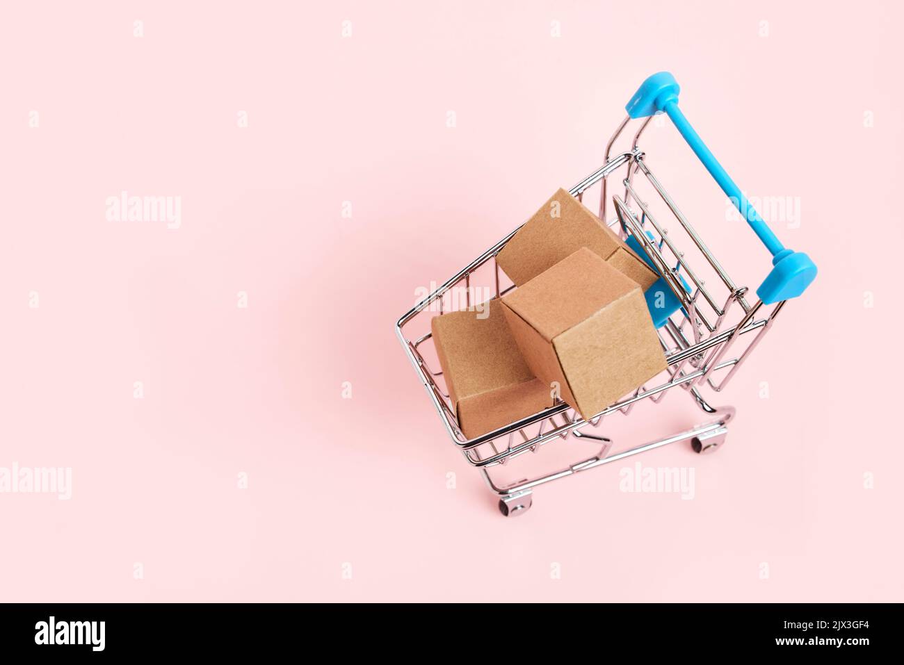 Shopping cart with cardboard boxes on a pastel pink background. Top ...