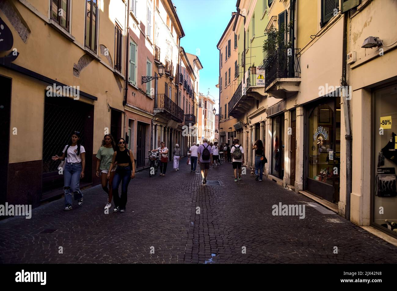 Paved street in the shade with shops and people strolling Stock Photo ...
