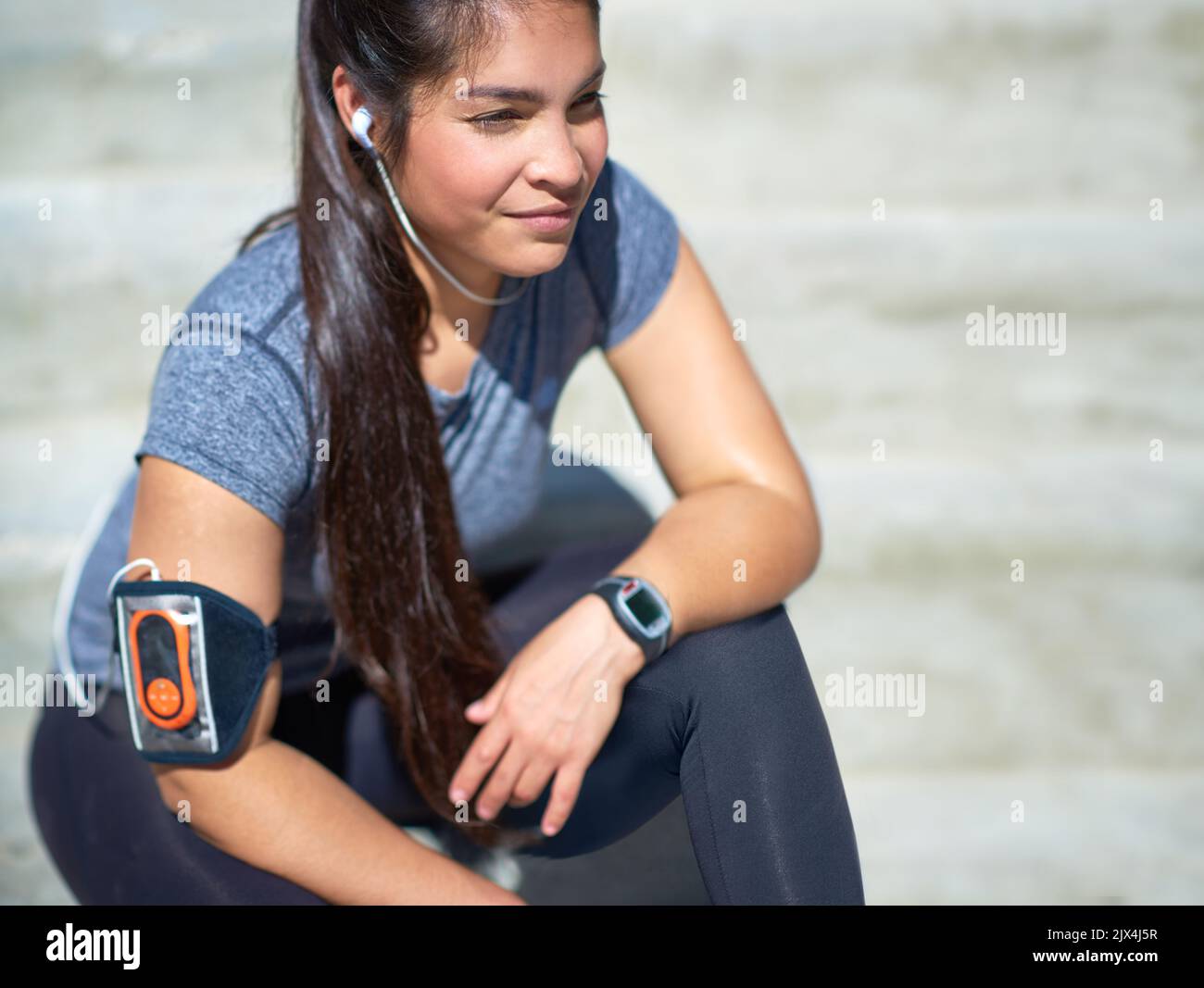Taking a break after a good run. a sporty young woman listening to ...