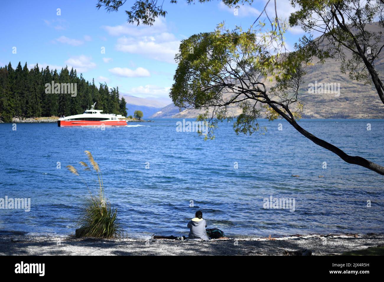 A woman rests on the shore of Lake Wakatipu in Queenstown, Wednesday ...