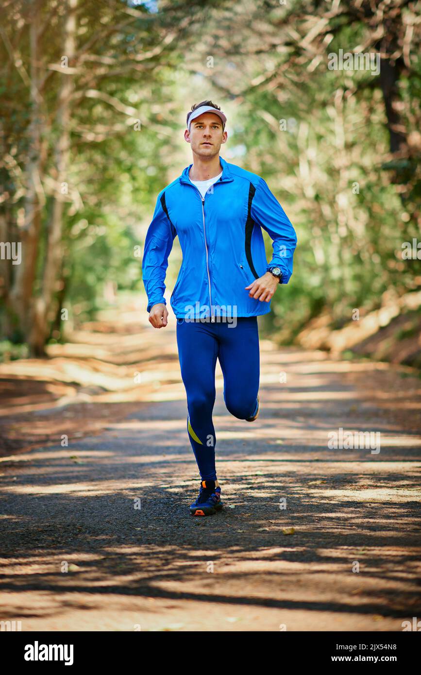 Running is a way of life. a young man running along a trail Stock Photo ...