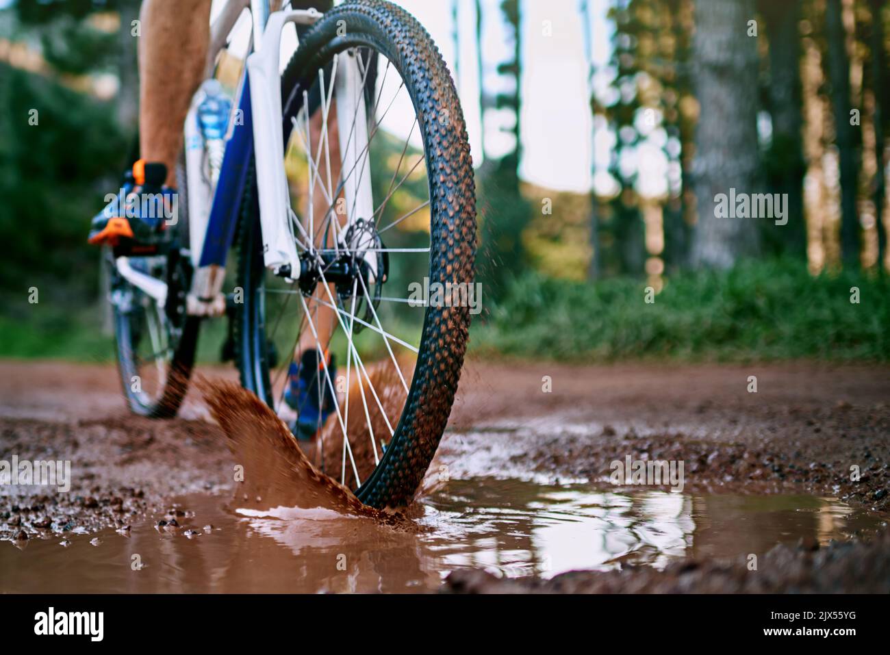 Getting dirty is part of the fun. a male cyclist riding along a muddy ... Getting dirty is part of the fun. a male cyclist riding along a muddy ...