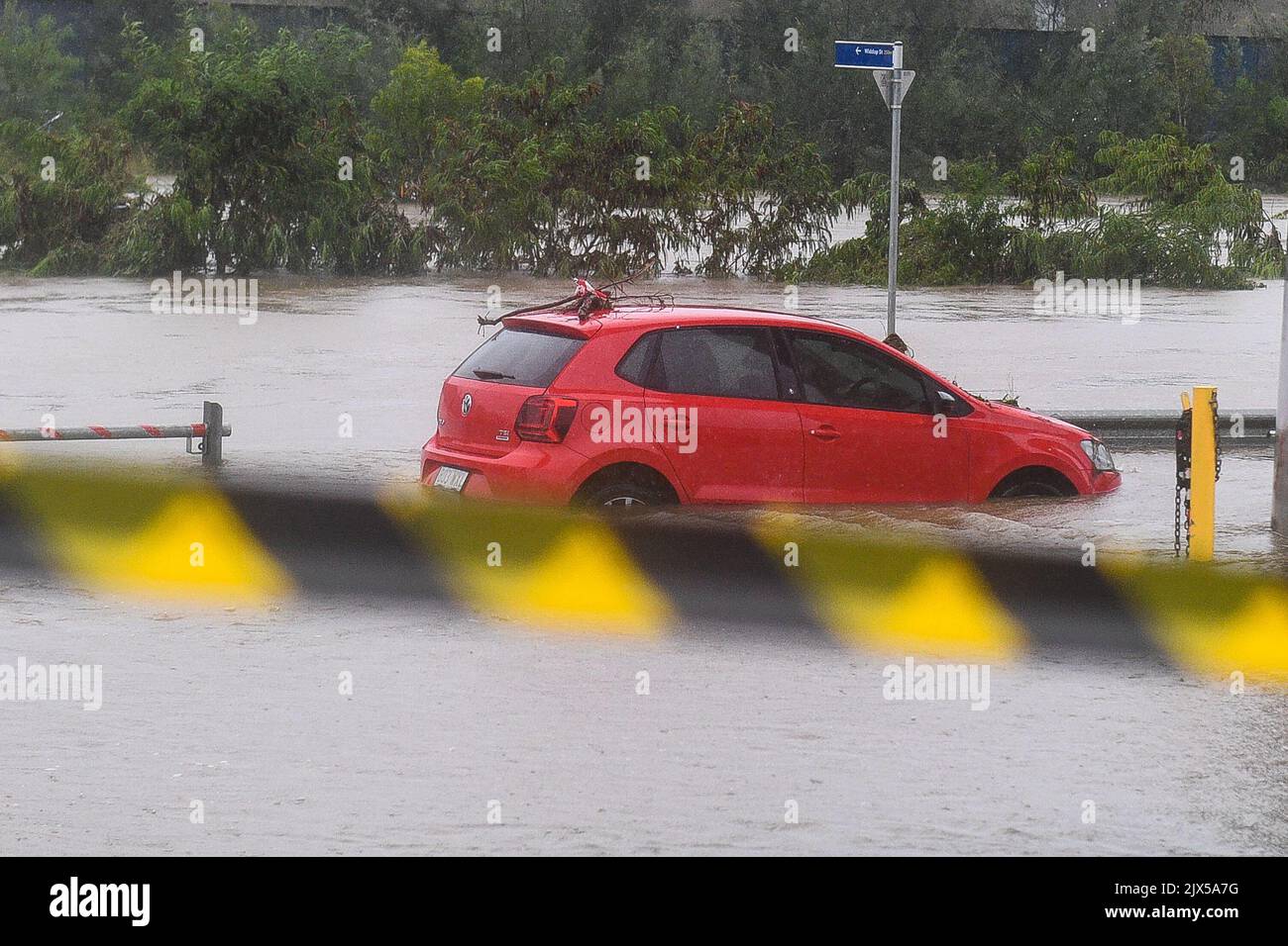 A car sits in flood waters in the Toombul Shopping Centre car park ...
