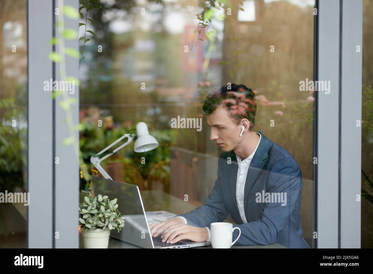 Concentrated young entrepreneur working on laptop in modern office ...