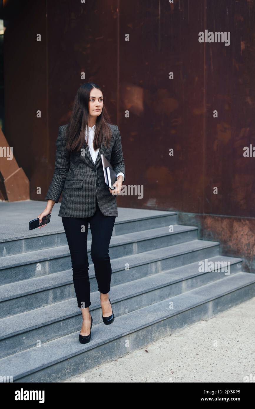 A businesswoman is leaving her office in a cluster of tall buildings ...