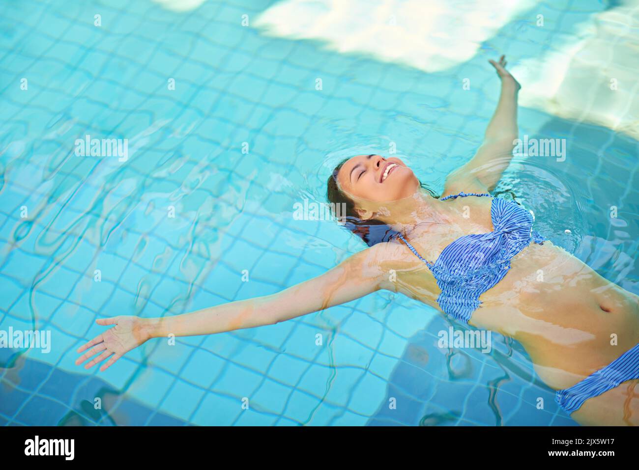 Floating into the big blue. a young woman relaxing in the pool at a spa Stock Photo - Alamy