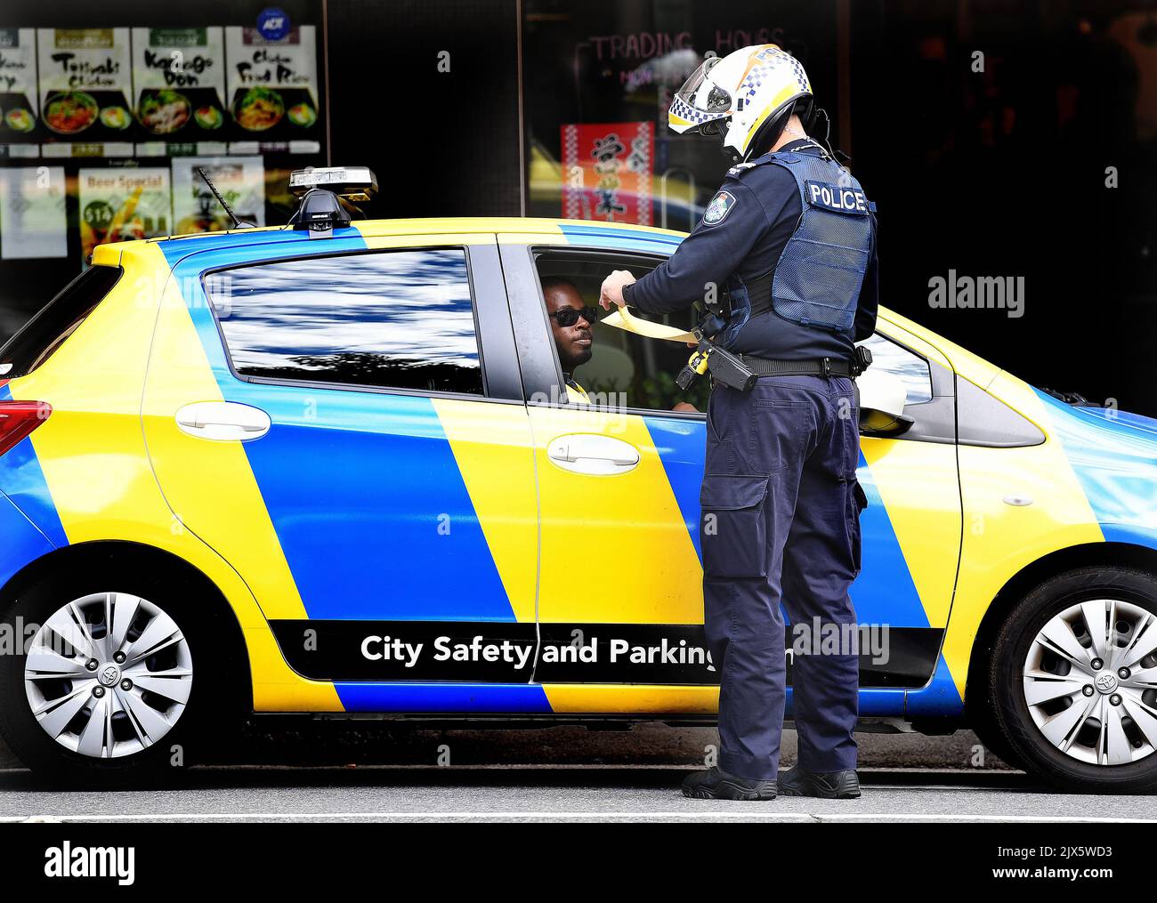 A police officer issues a traffic infringement fine to a Brisbane City ...