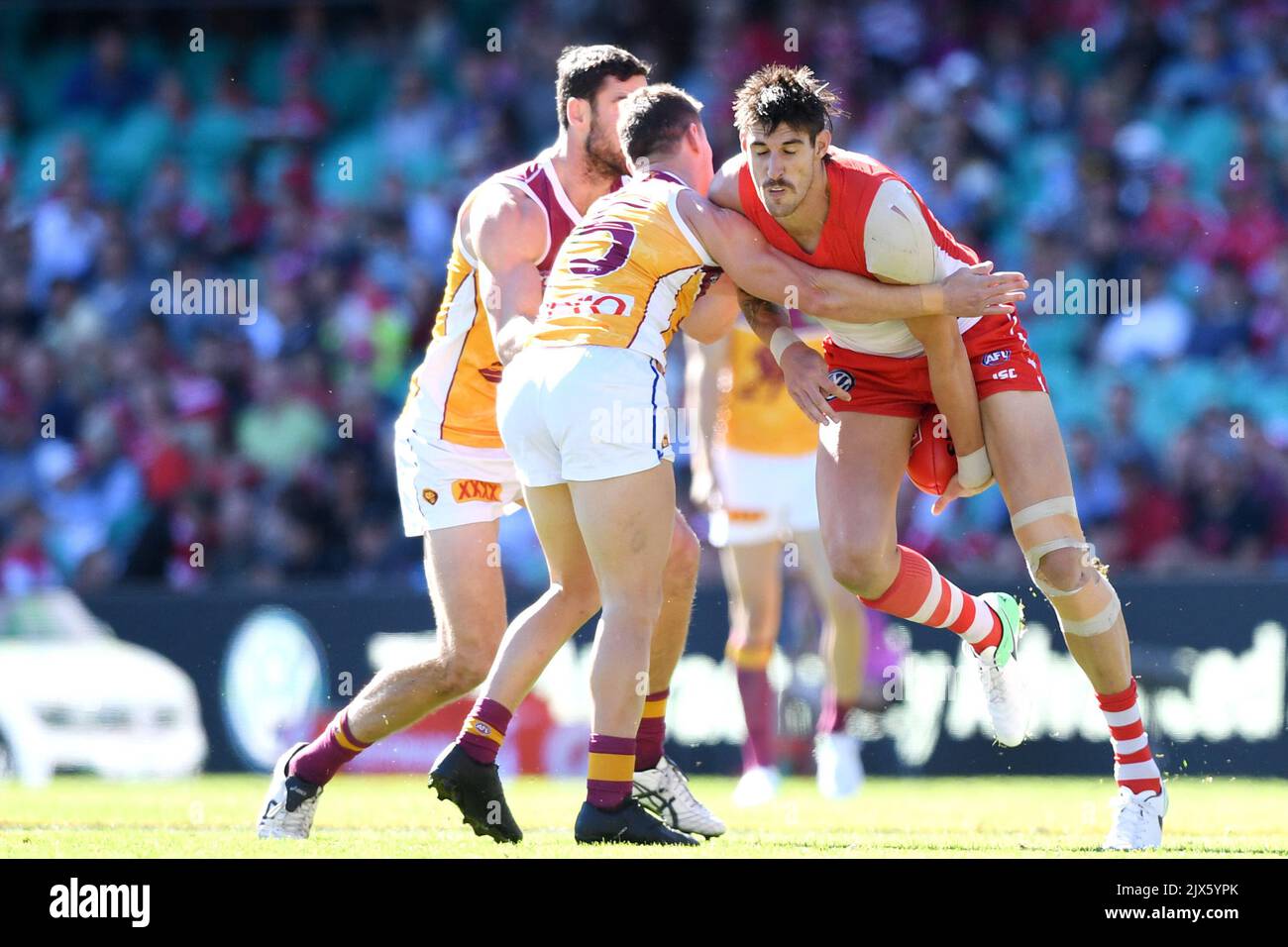 Sam Naismith (right) of the Swans is tackled by Dayne Zorko (centre) of ...