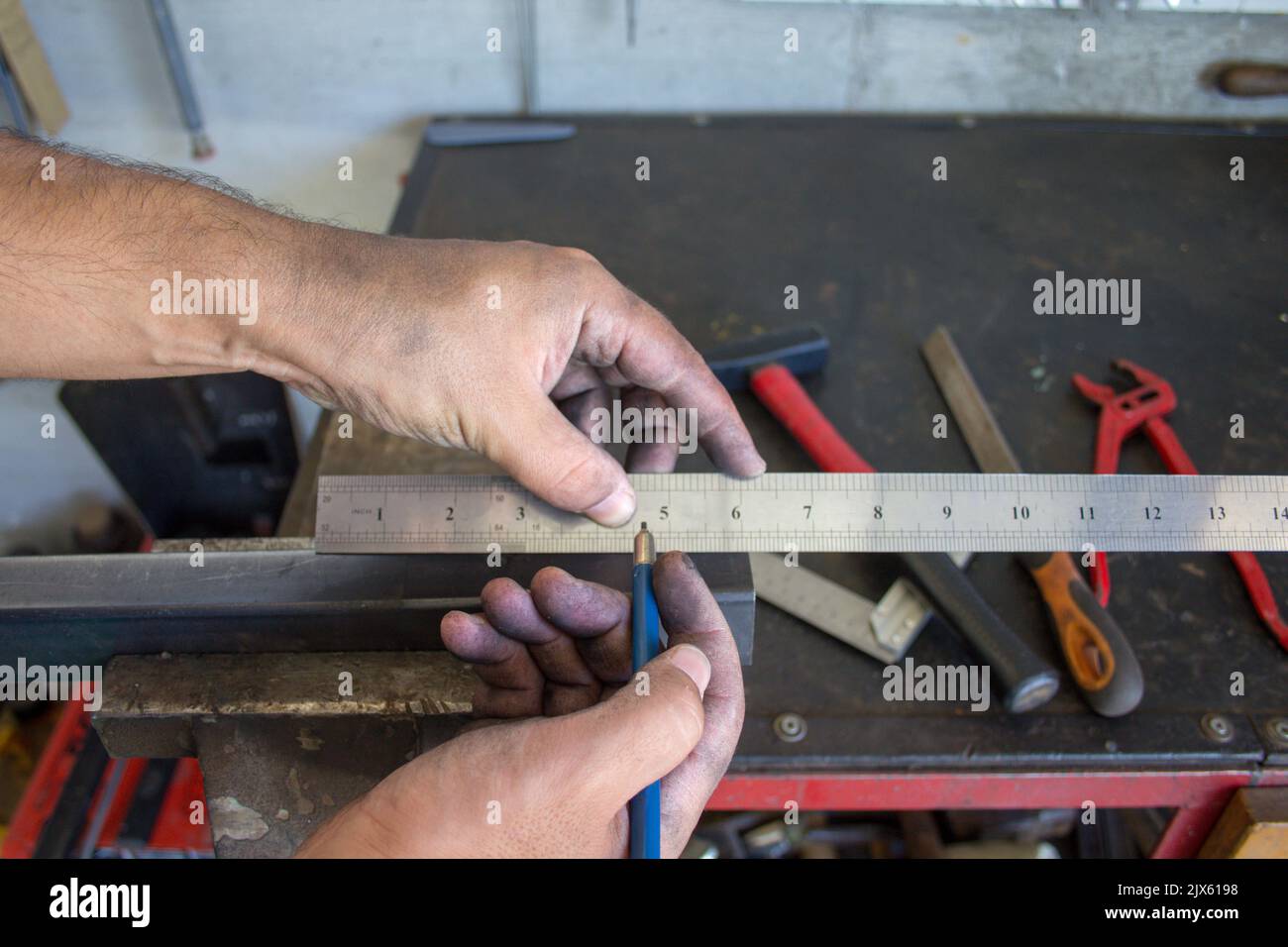 Image of the dirty hands of a blacksmith who with a ruler and a pencil ...