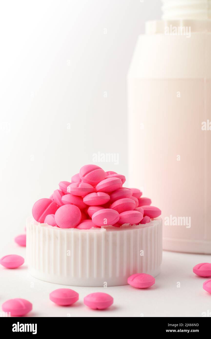 pink round pills or tablets on white background with bottle or ...