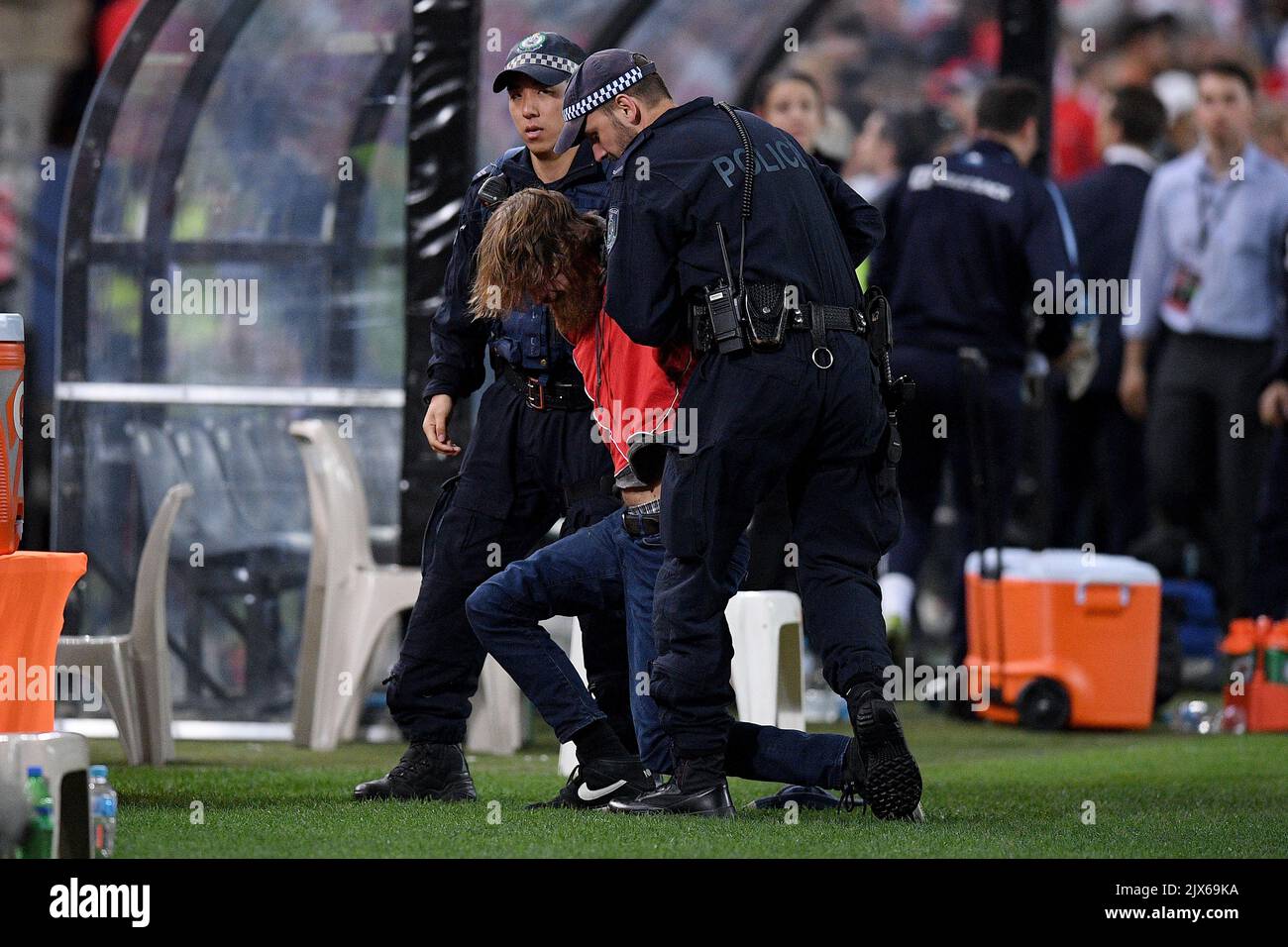 A pitch invader is removed by Police following the exhibition match ...