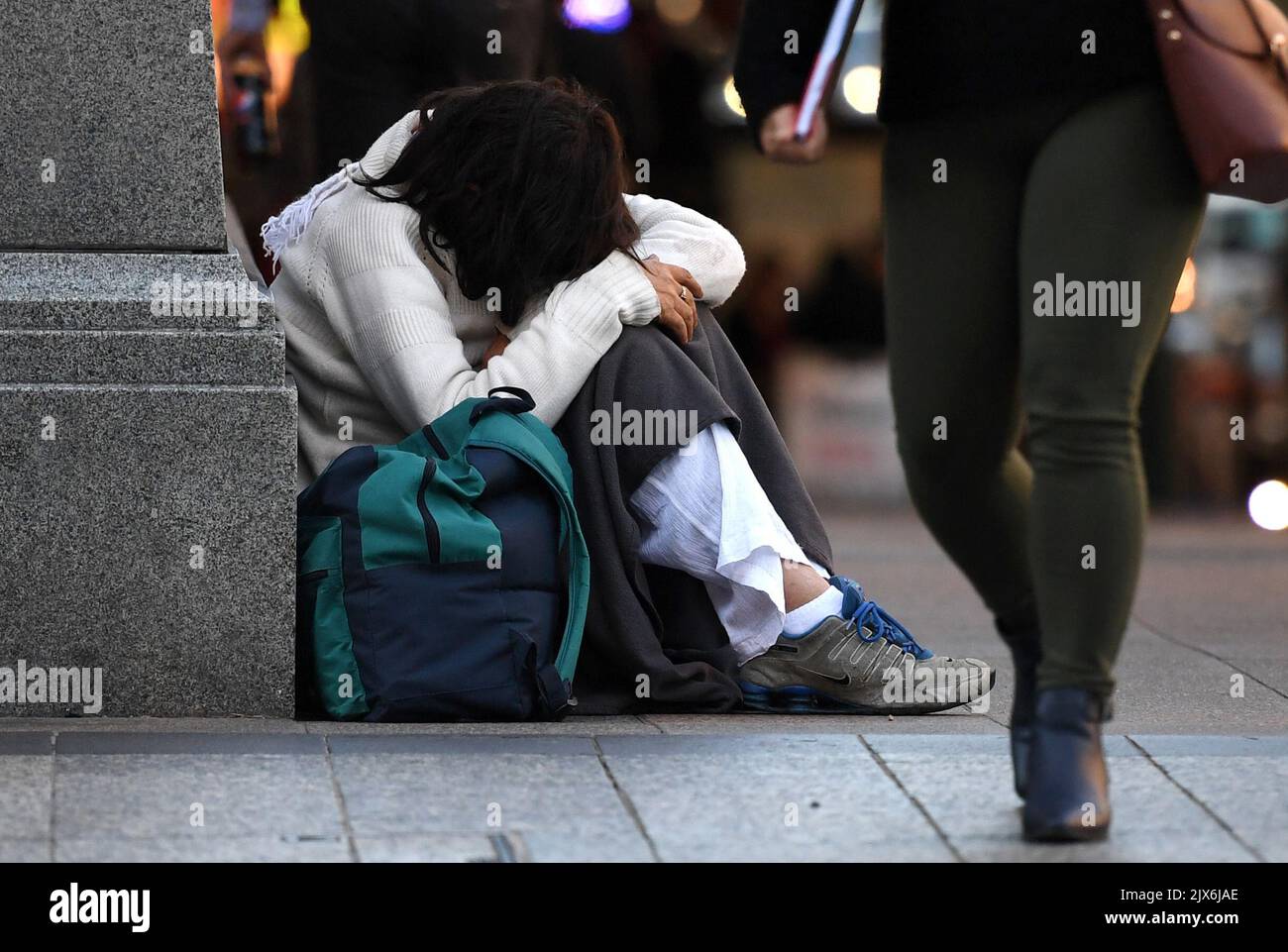 A homeless woman sits on a street corner in central Brisbane, Friday ...