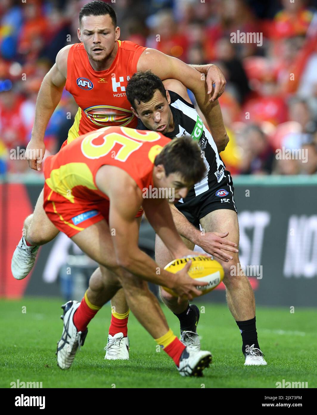 Jarryd Lyons of the Gold Coast Suns (front) takes the ball ahead of ...