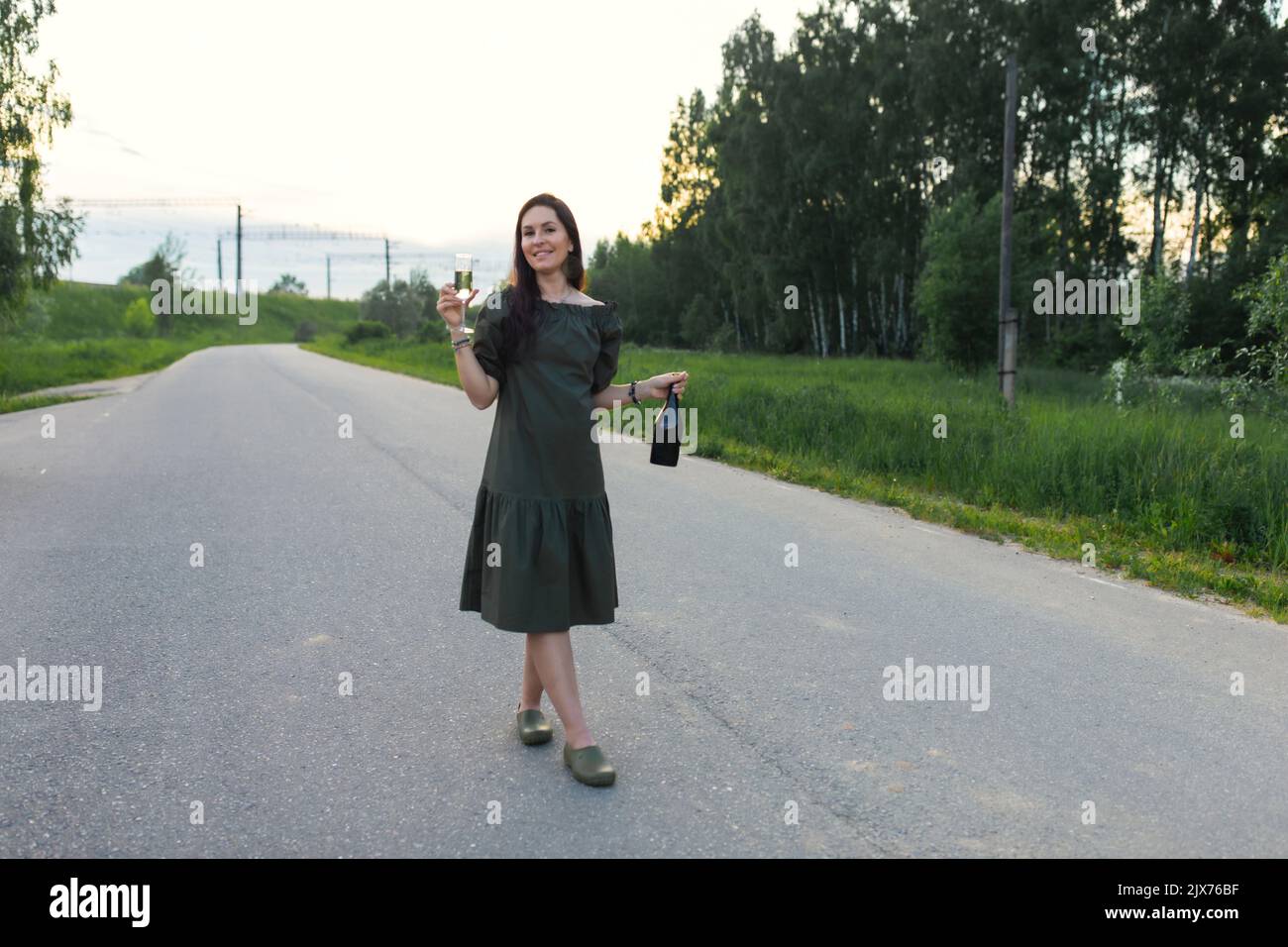 An attractive woman with a bottle and a glass of champagne is walking ...